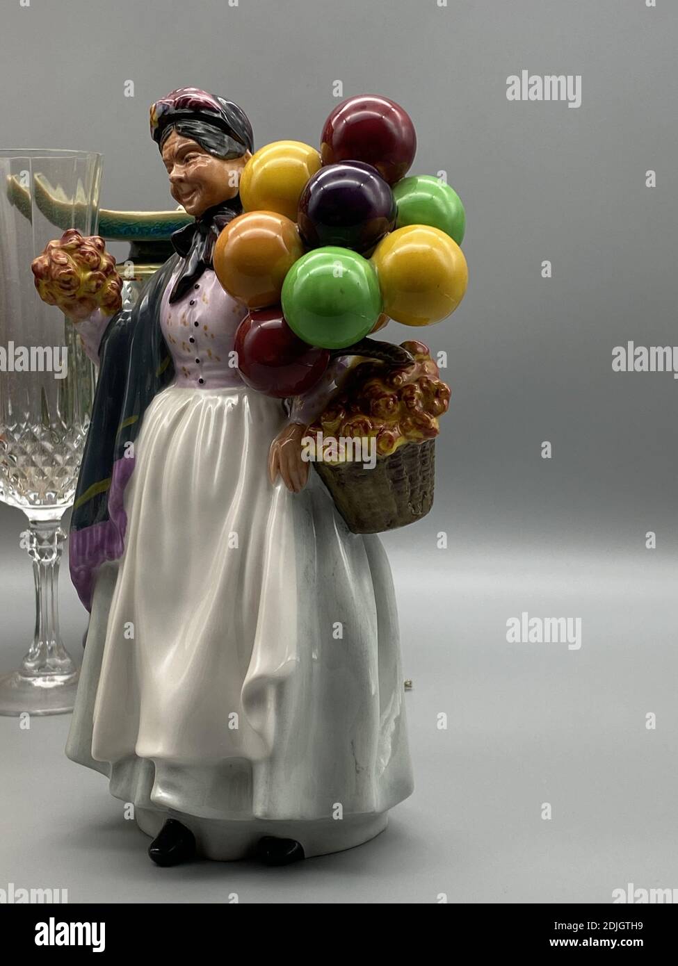 A vertical shot of an old woman porcelain figurine holding balloons ...