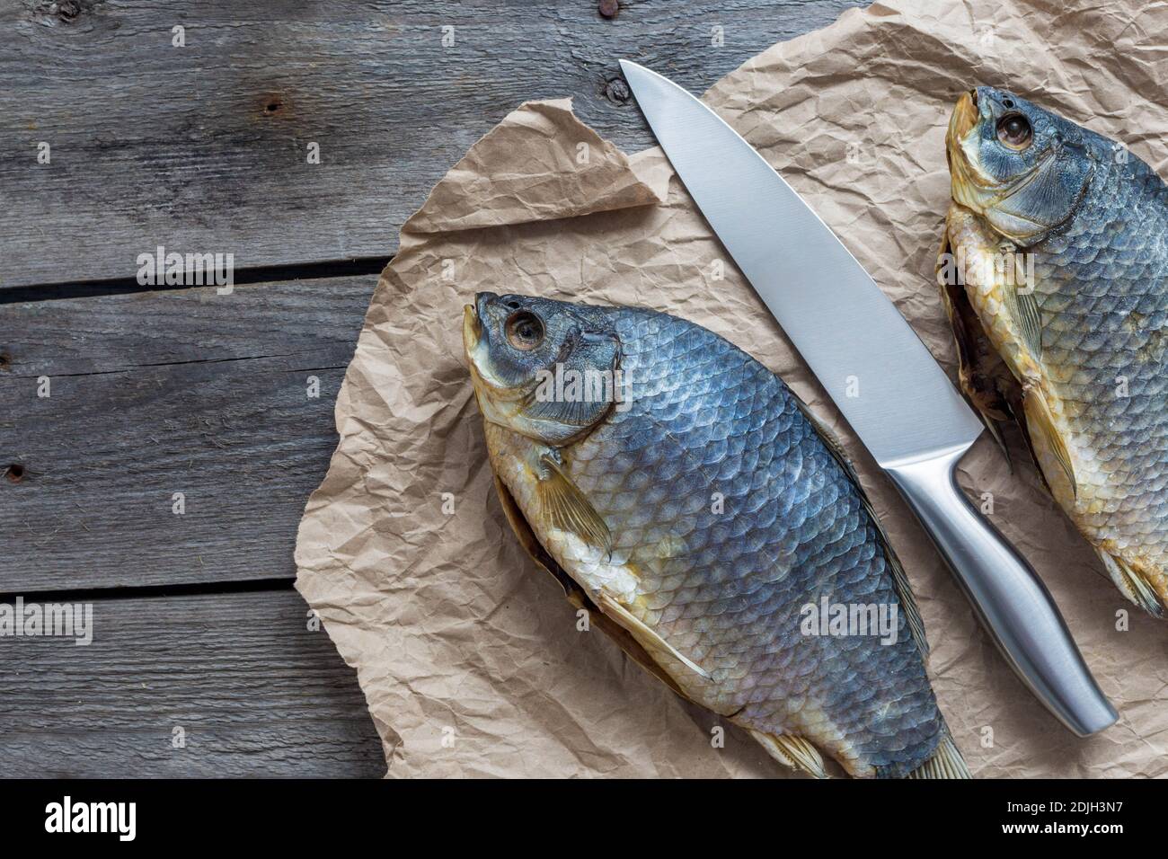 Salted Dry fish vobla with a sharp knife on crumpled craft paper on ...