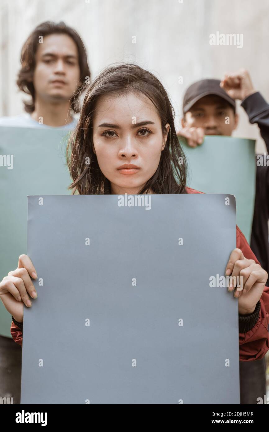 Portrait female students demonstrating with their friends holding blank ...