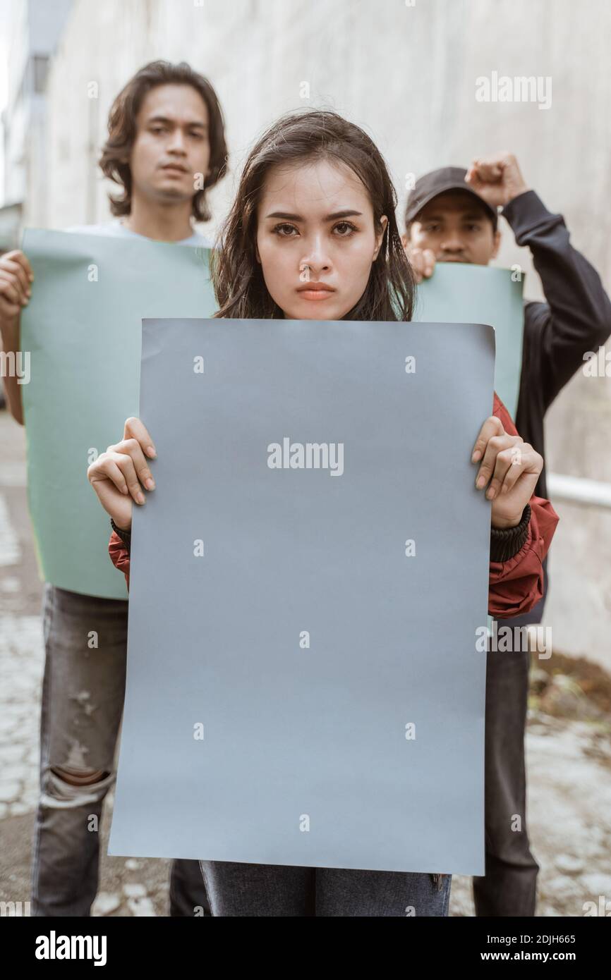 Portrait female students demonstrating with their friends holding blank ...