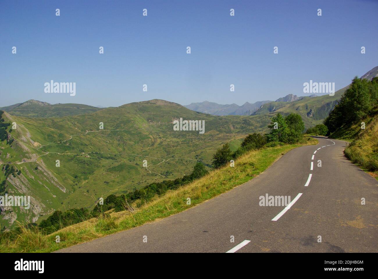 Mountain road surrounded by green meadows through the French Pyrenees ...