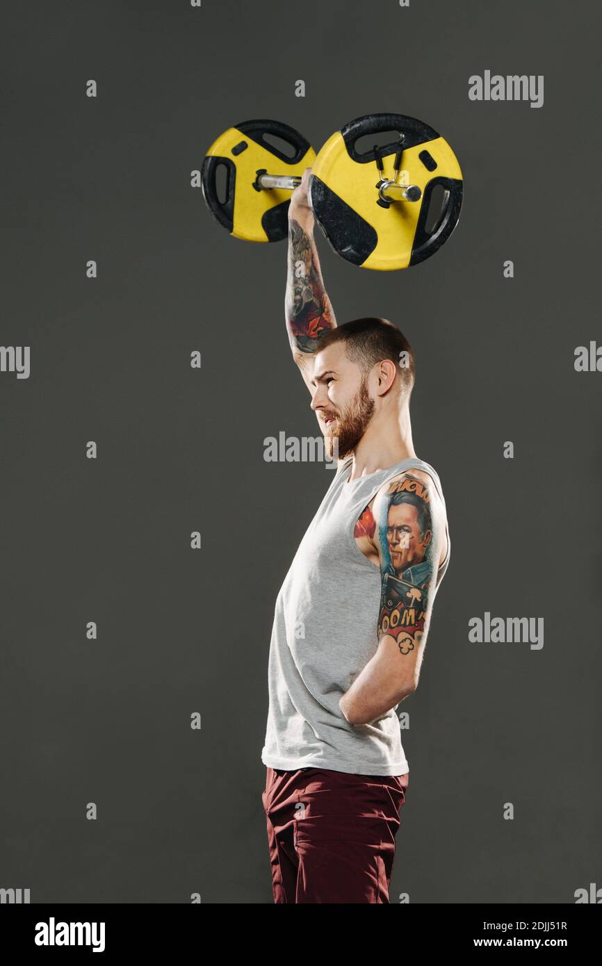Hard-working armless man lifting adjustable dumbbell overhead with one ...