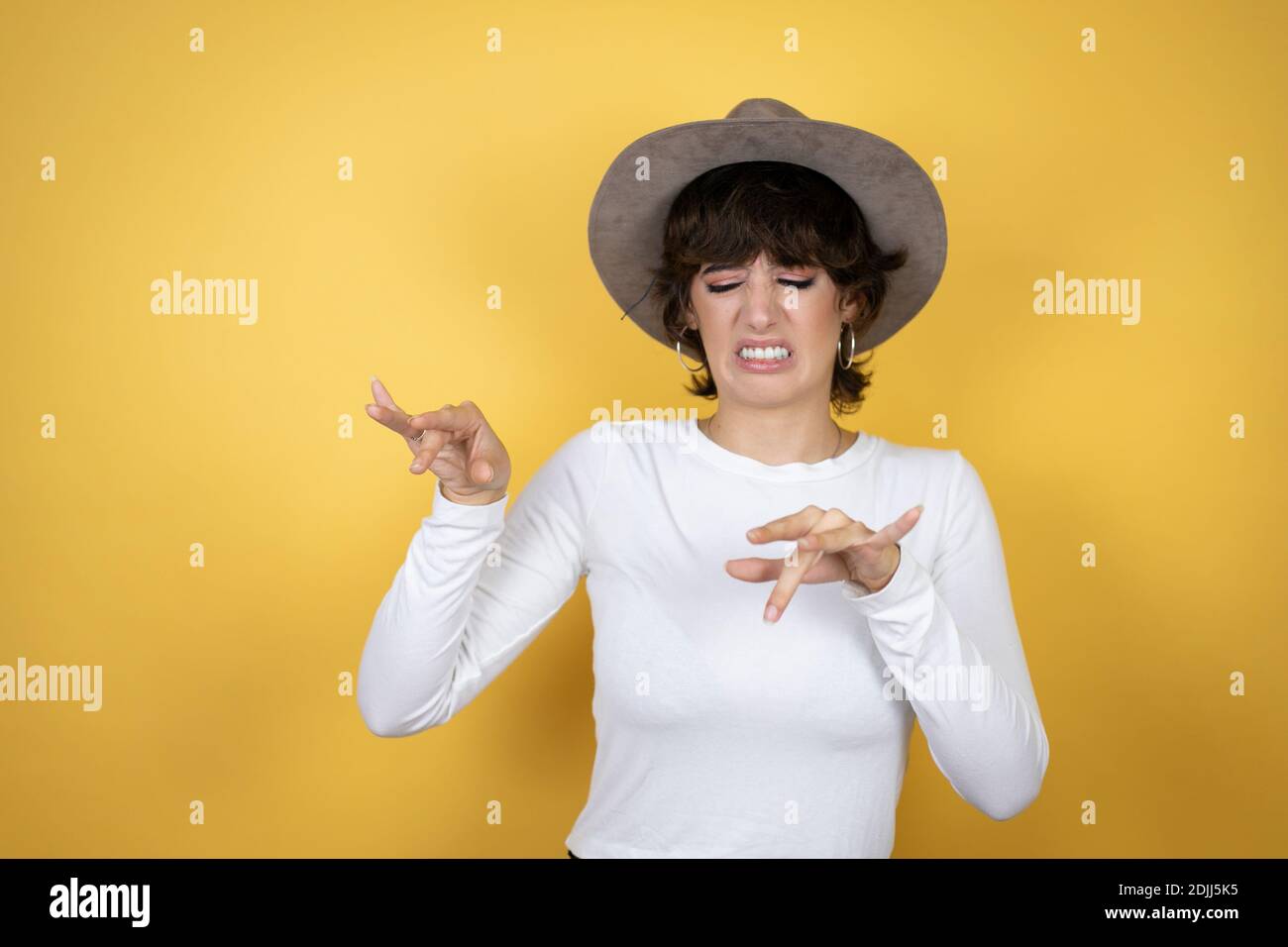 Young caucasian woman wearing hat over isolated yellow background ...