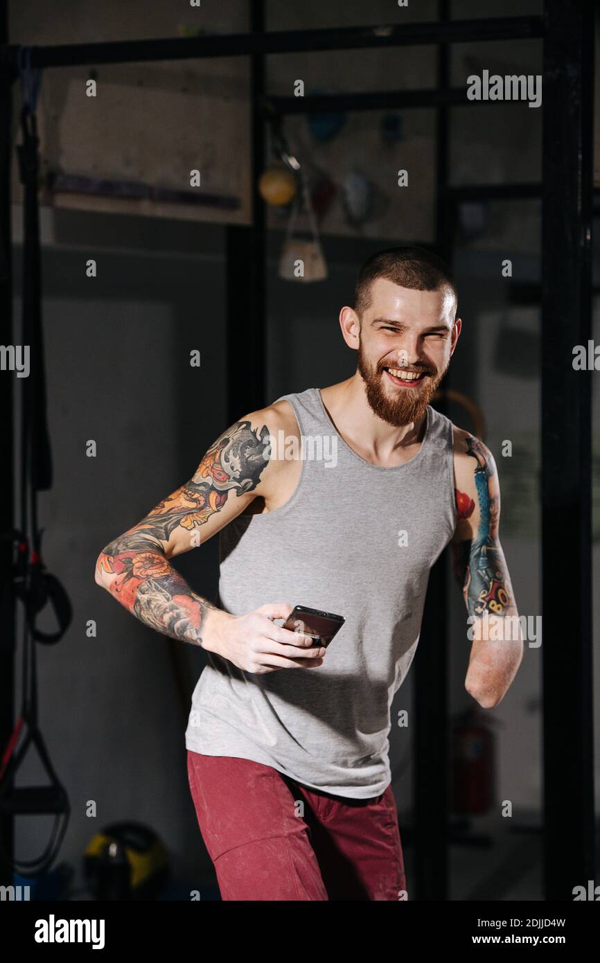 Happy young disabled armless man in a training room with a phone in ...