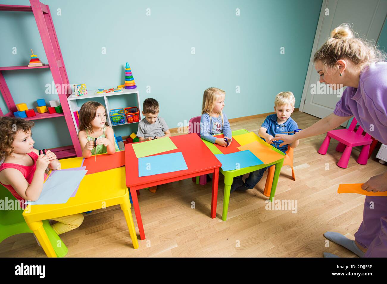 The tutor teaches kids how to cut out of colored paper Stock Photo - Alamy