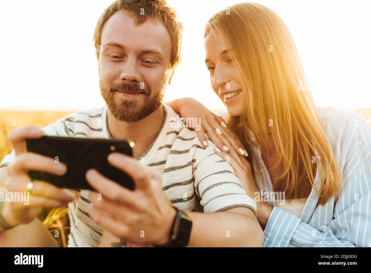 Image of a young happy positive loving couple using mobile phone ...