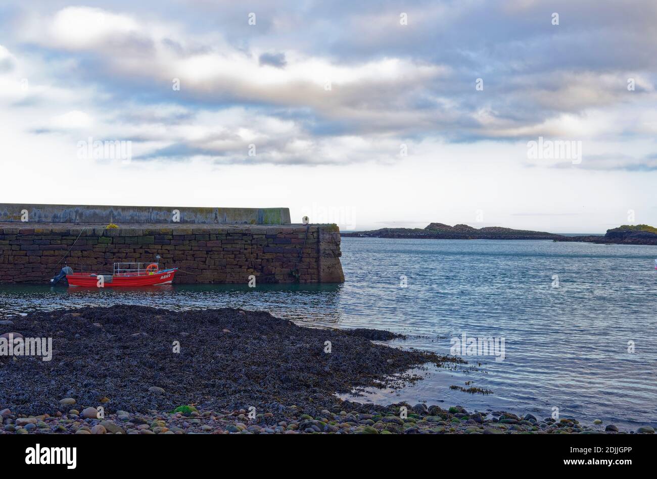 A small wooden Fishing boat with a reed hull moored up alongside the ...