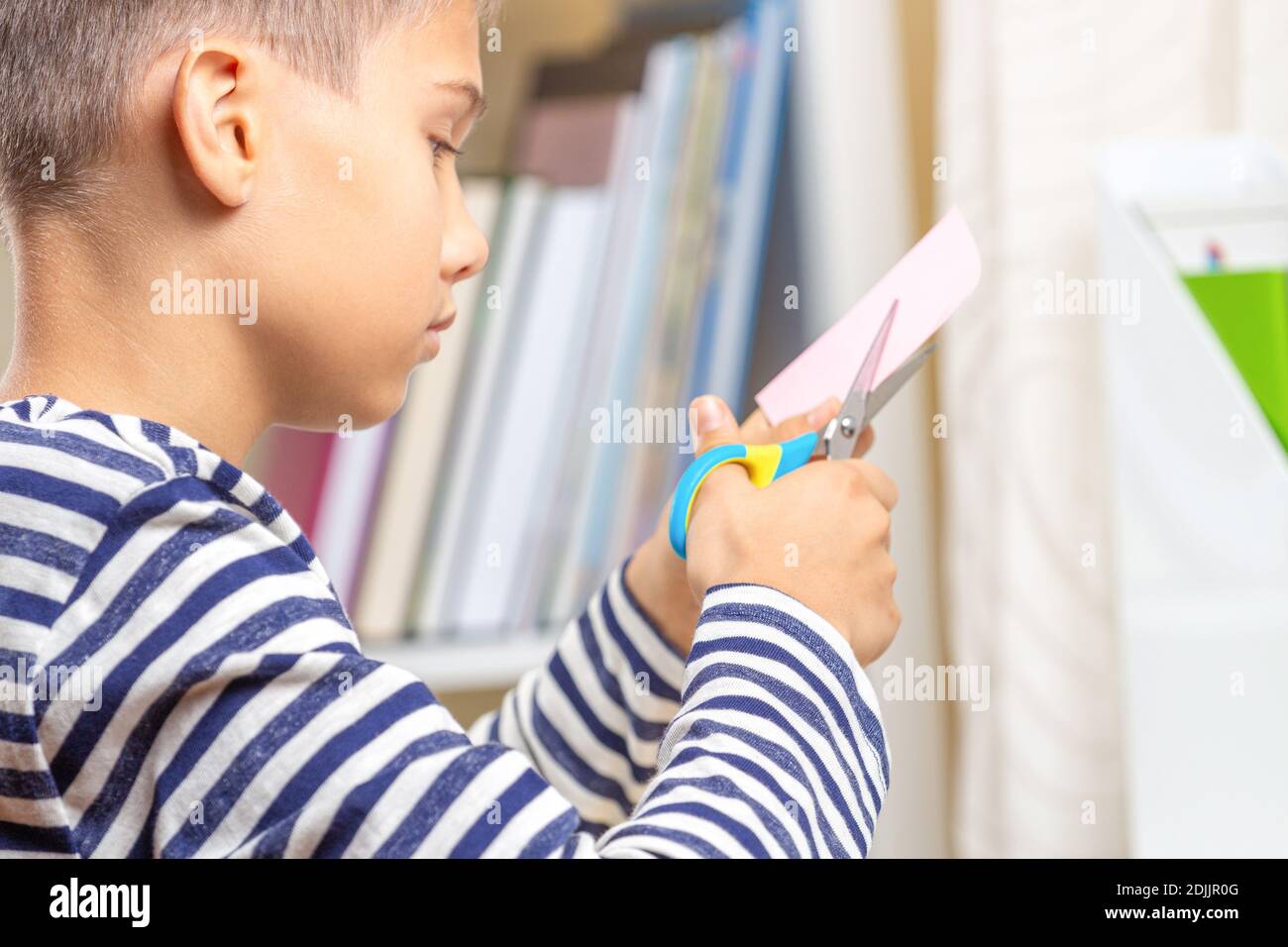 Teenage boy cutting colored paper with scissors. Kid looking video ...