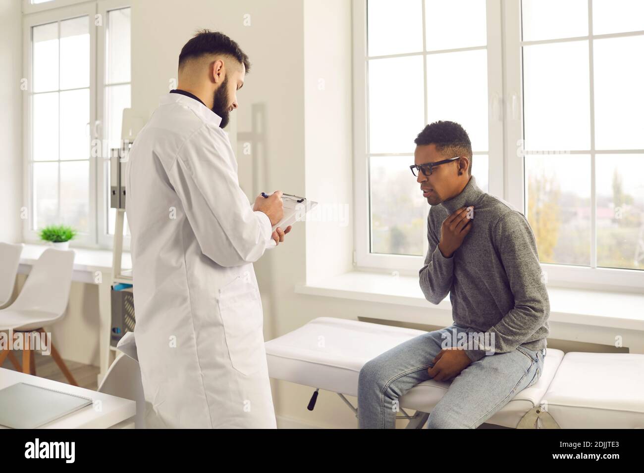 Young Patient Telling Doctor About His Sore Throat And Cough During Visit To Hospital Stock