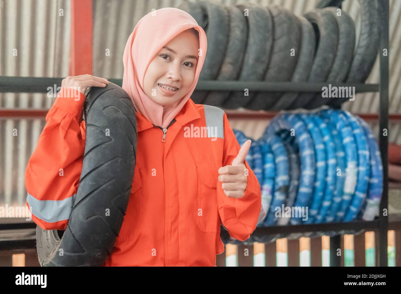 veiled female mechanic wears a wearpack uniform with a thumbs up when ...