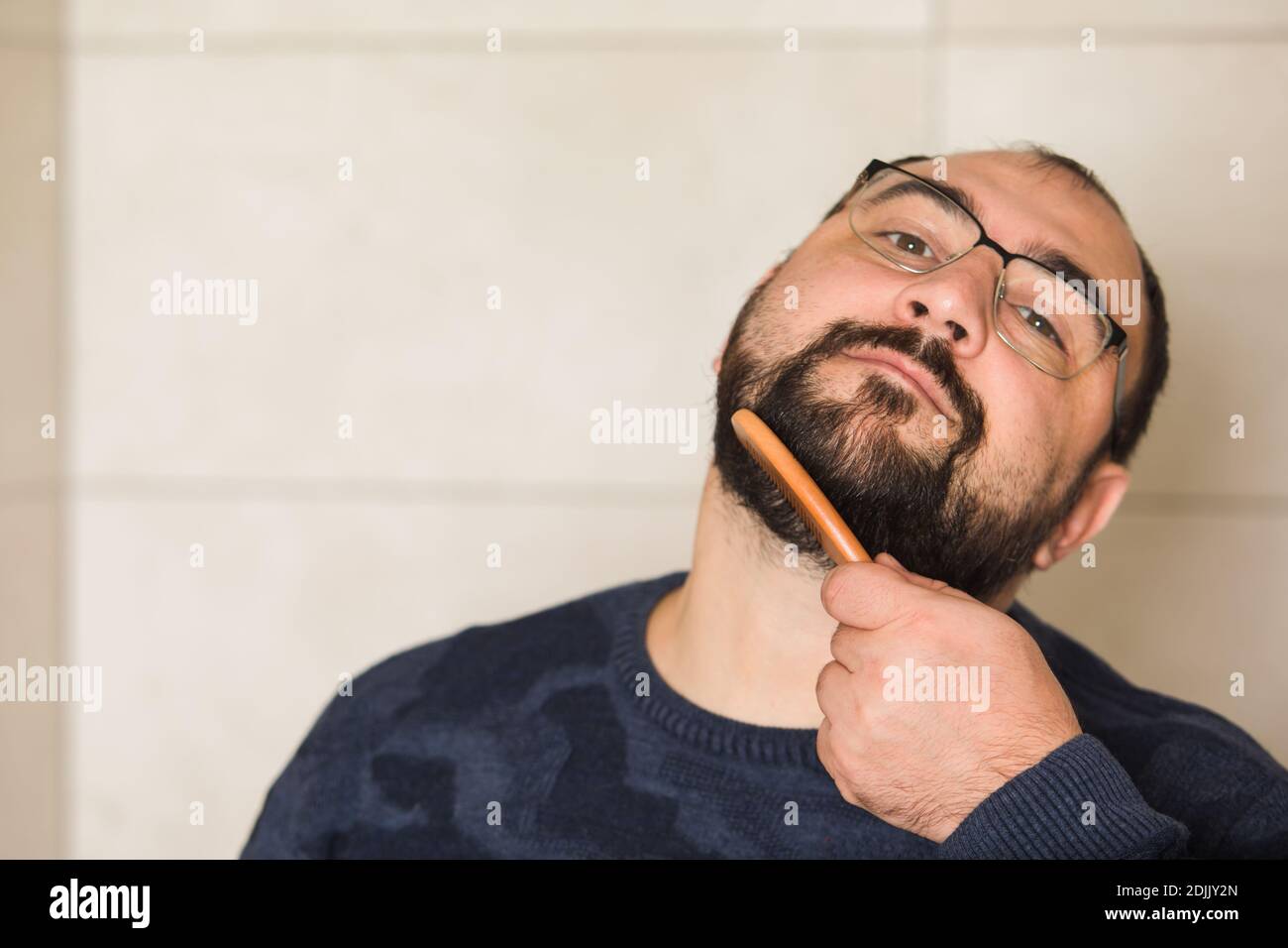 Man in glasses comb his beard indoor Stock Photo - Alamy