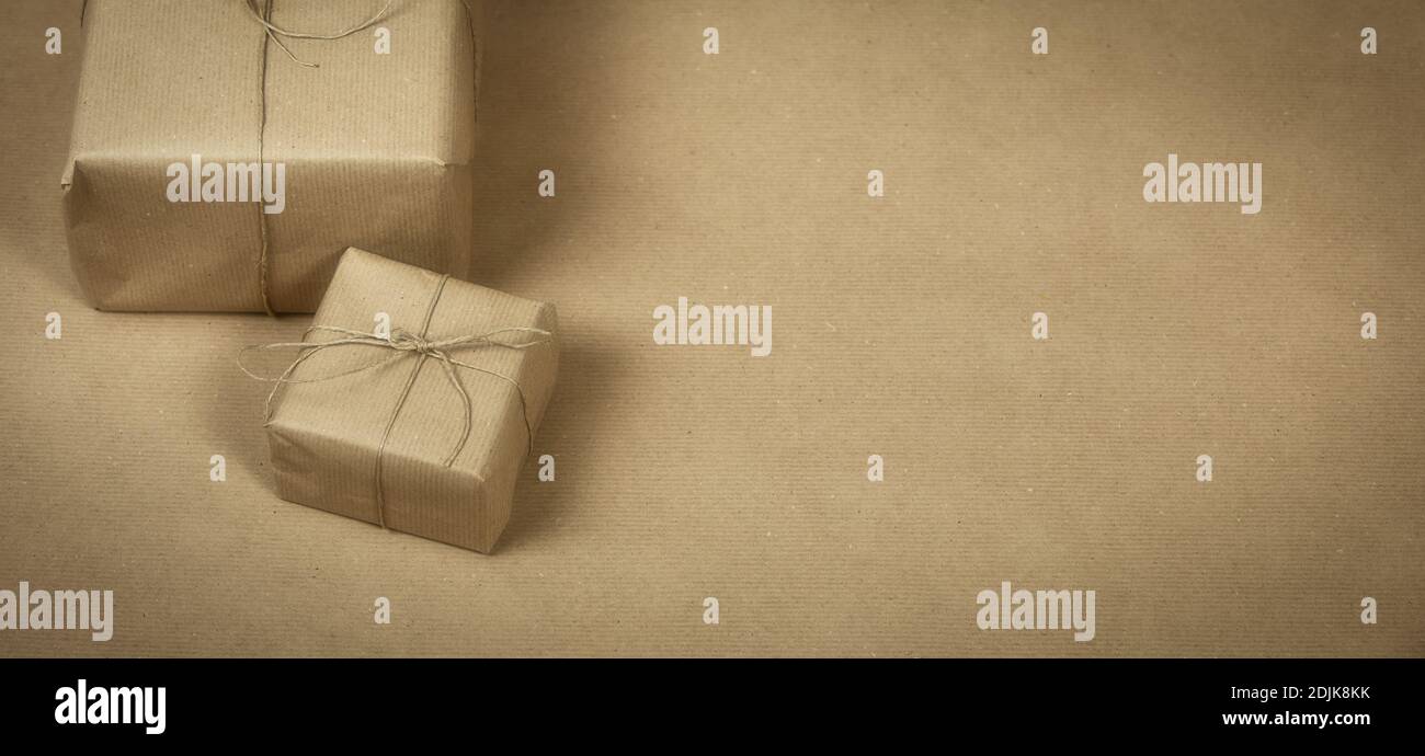 two gift package wrapped with plain brown paper and rope and brown ...