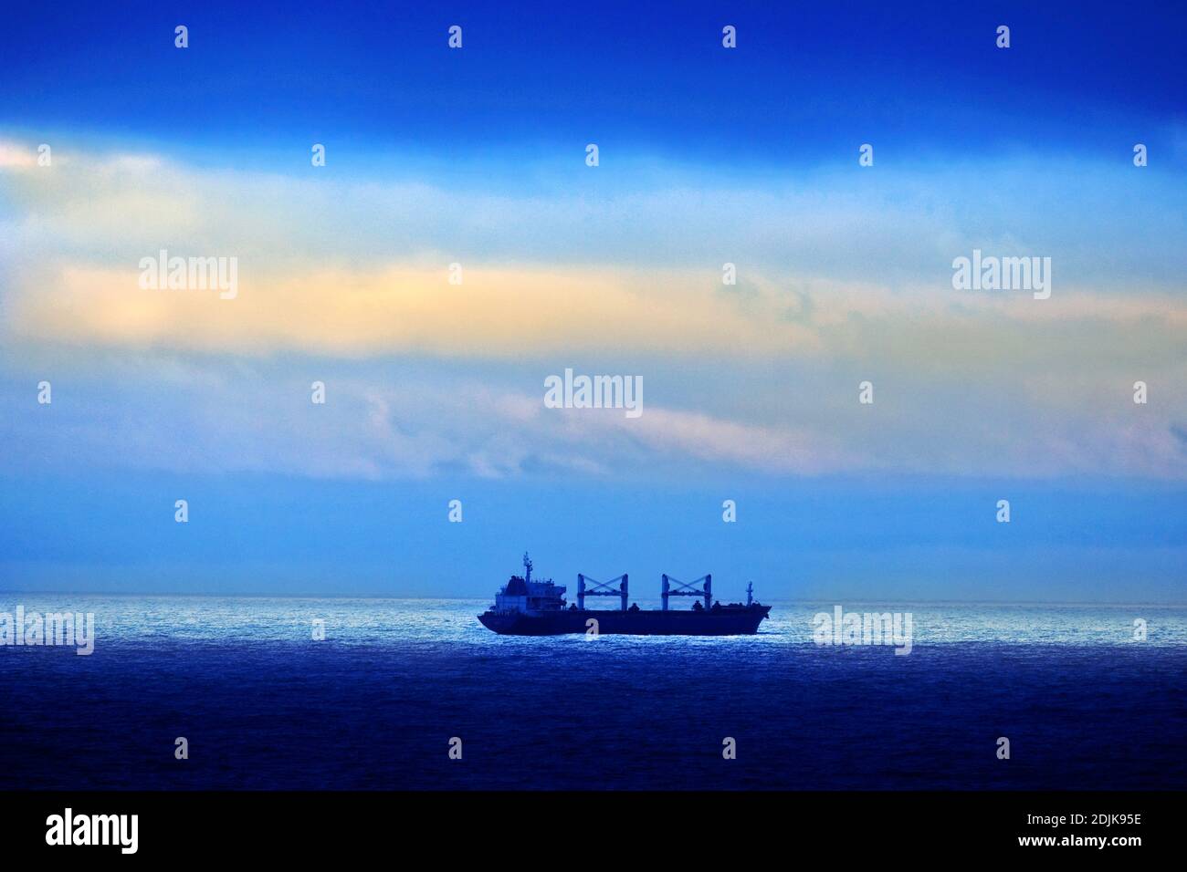 Merchant cargo ship with colourful cloud formation at sea Stock Photo ...