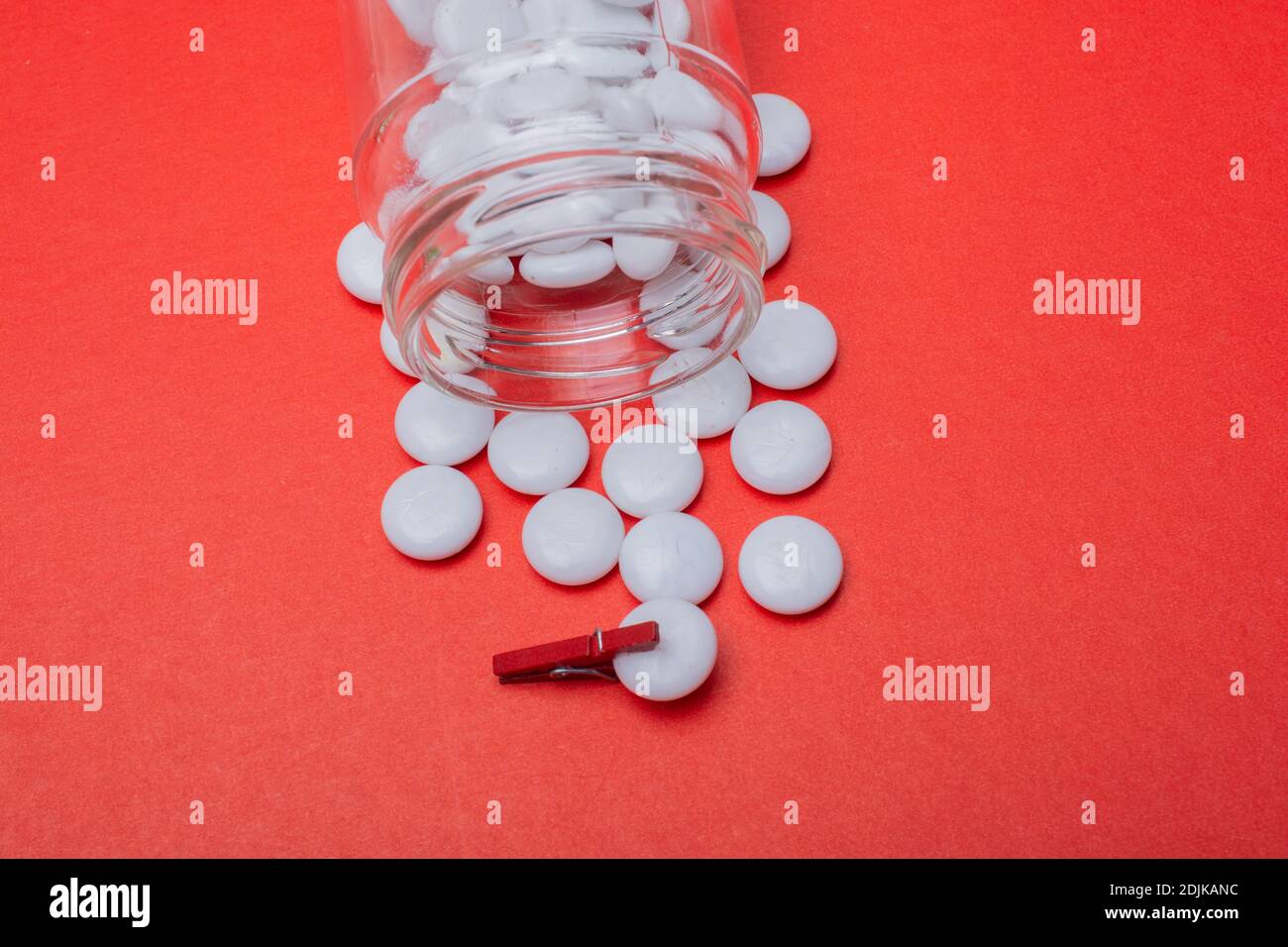White medical pills spilling out of pills bottle, red background ...