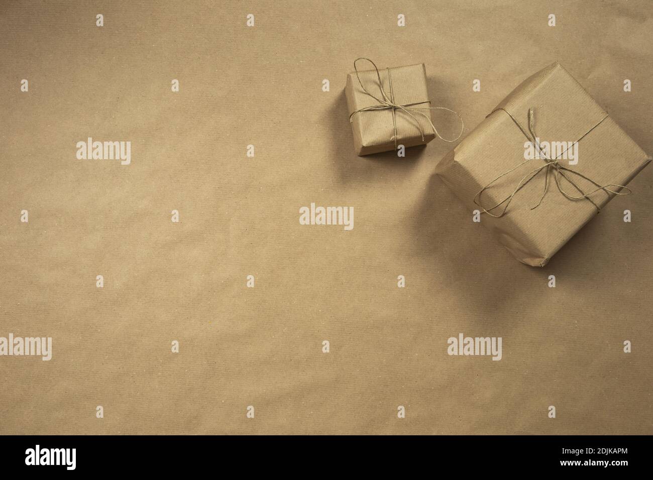 Two gift boxes wrapped in plain brown recycled paper with rope on brown ...