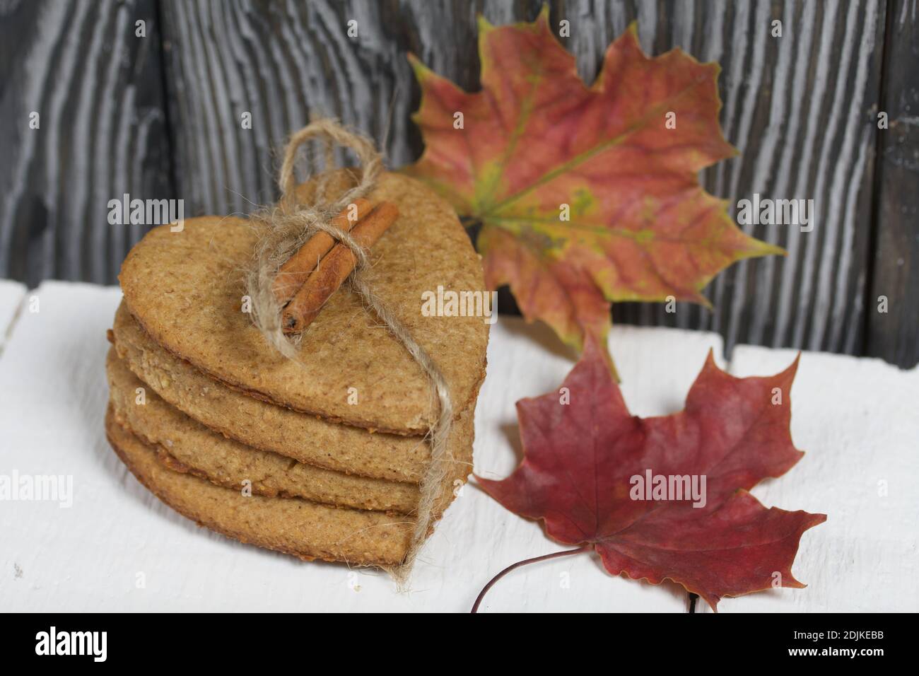 Gingerbread cookies tied with twine and autumn maple leaves. On boards ...