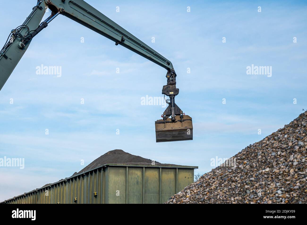 Big excavator working by handling pebbles from the pile of stones to ...