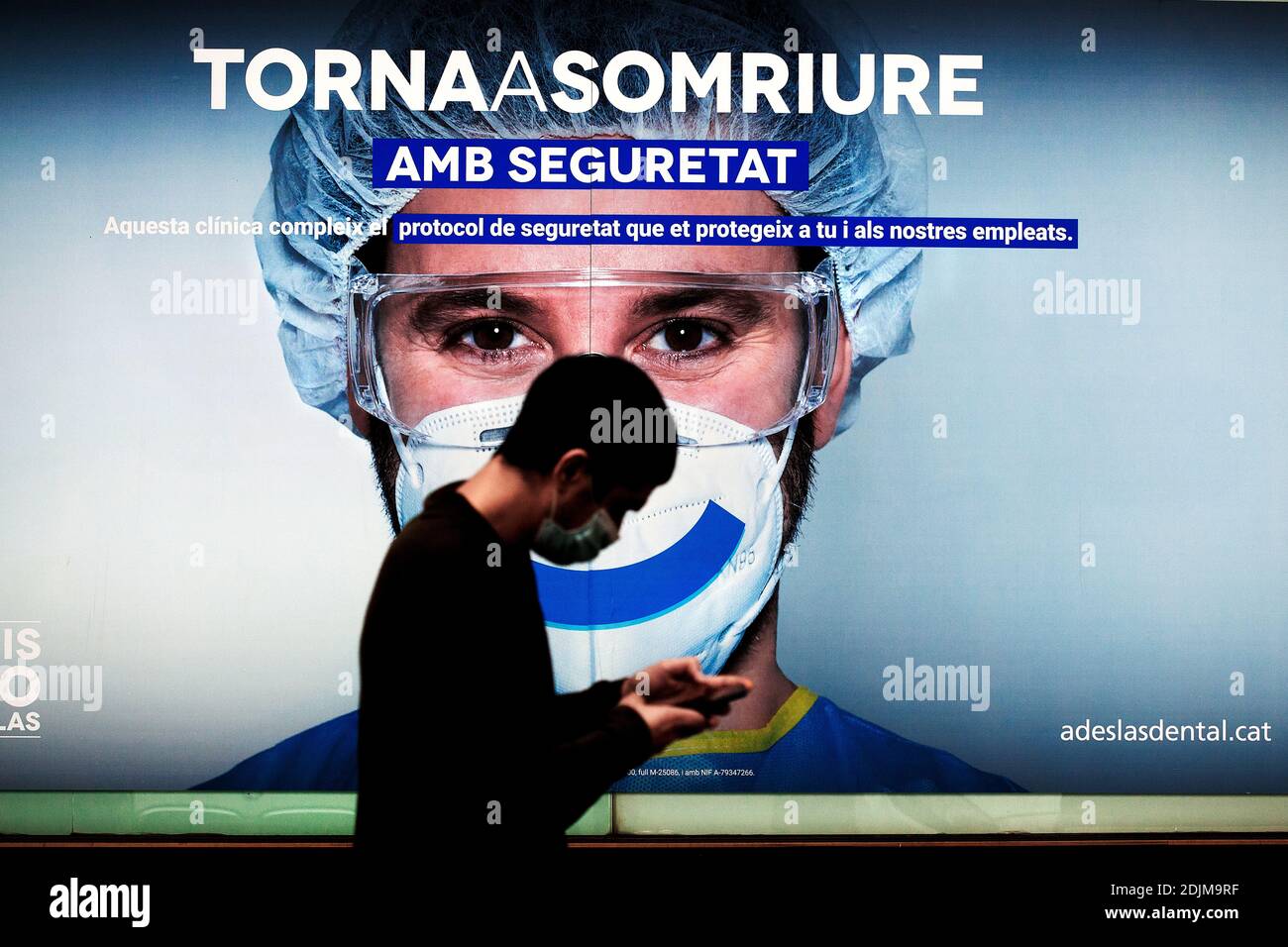 Man walking past an ad whilst looking at his smartphone, Barcelona ...