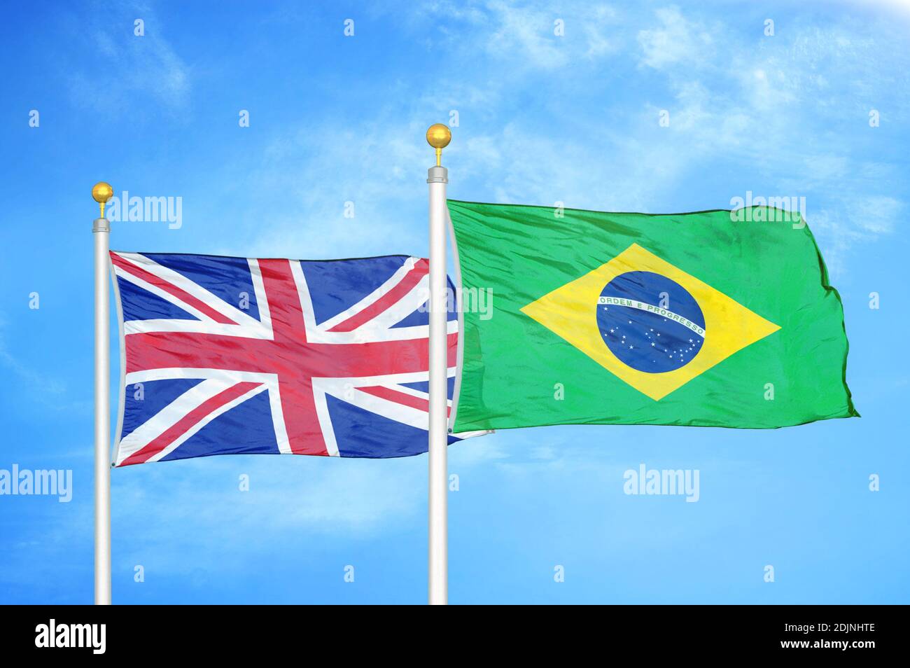 United Kingdom and Brazil two flags on flagpoles and blue cloudy sky ...