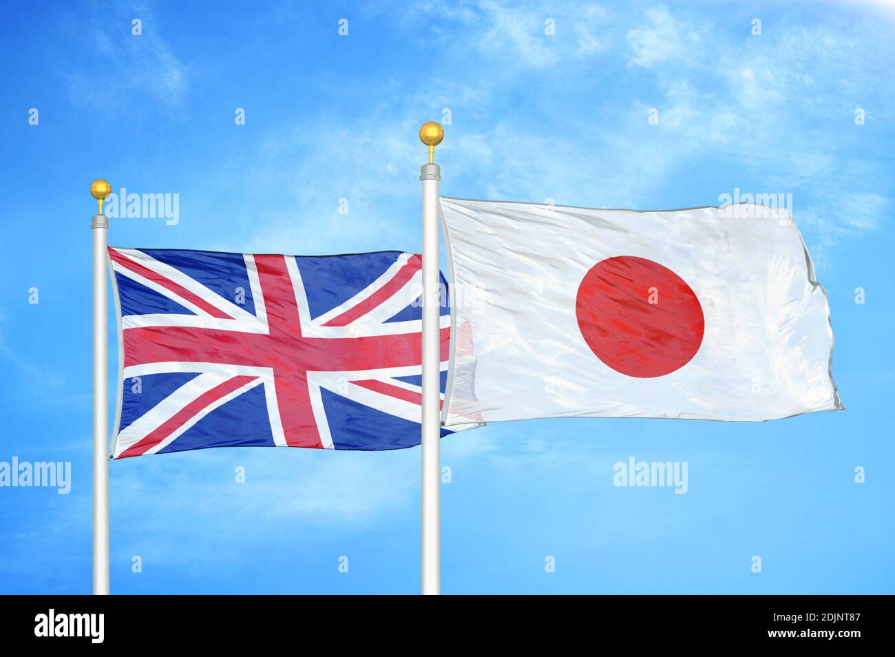 United Kingdom and Japan two flags on flagpoles and blue cloudy sky ...