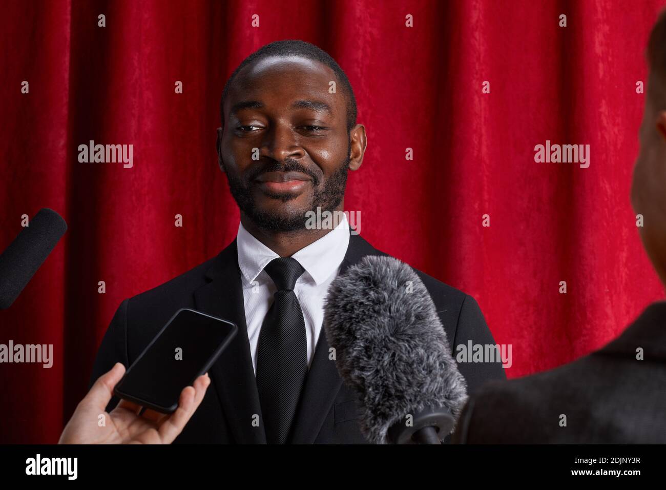 Portrait of smiling African-American man giving interview to journalist ...