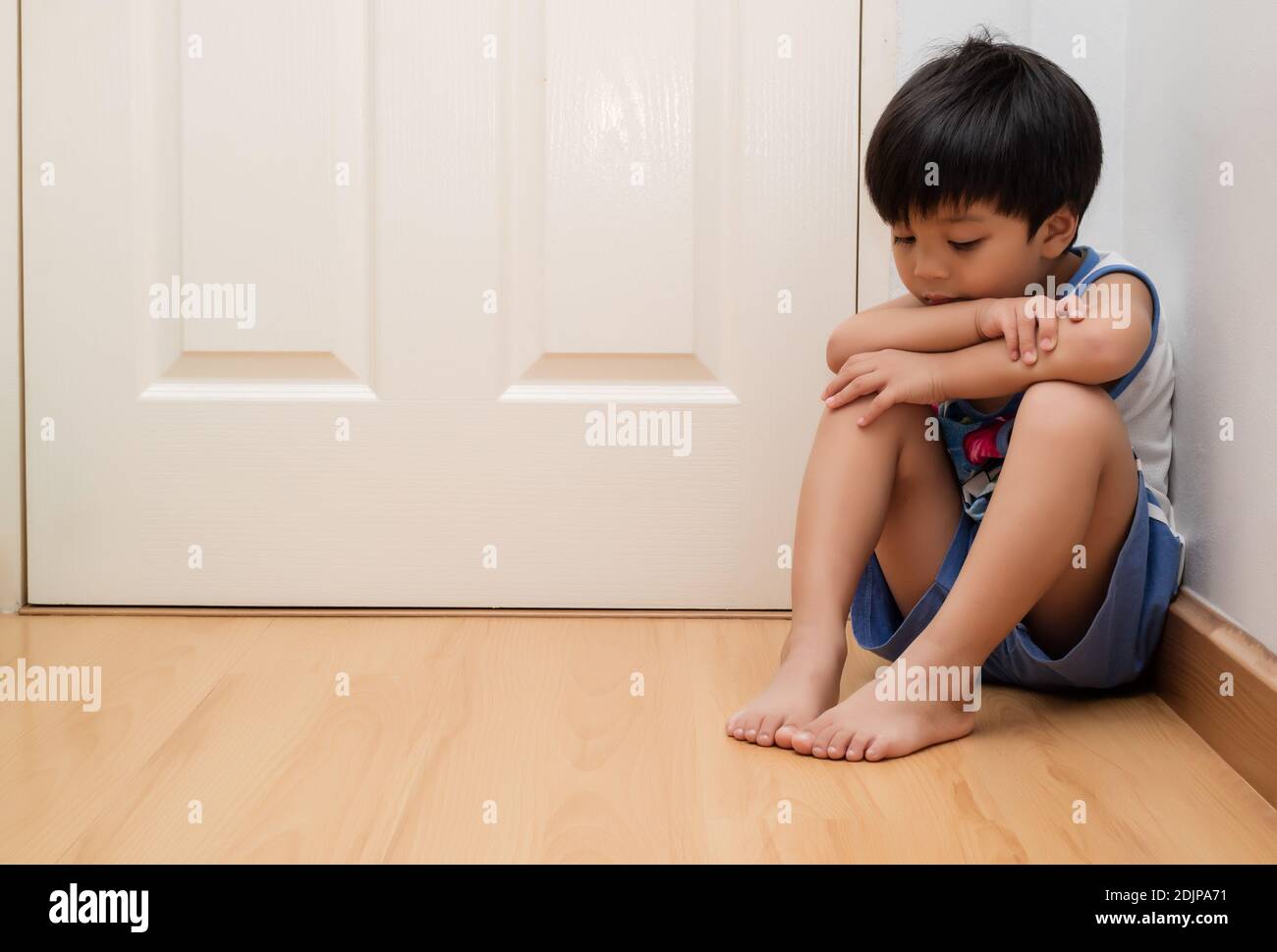 Full Length Of Boy Sitting Against Door At Home Stock Photo - Alamy