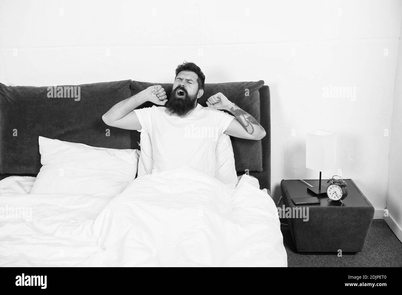 Weekend rest. Man stretching in bed. Carefree guy enjoying morning ...