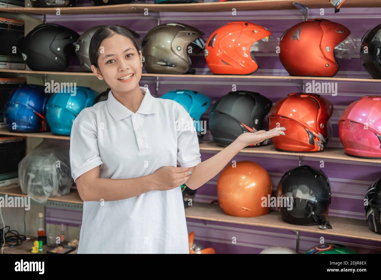 female shop assistant smiling with hand gestures to offer something in ...
