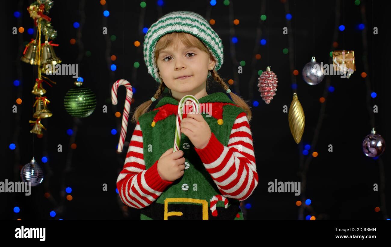Blonde kid girl in Christmas elf Santa Claus helper costume licking ...
