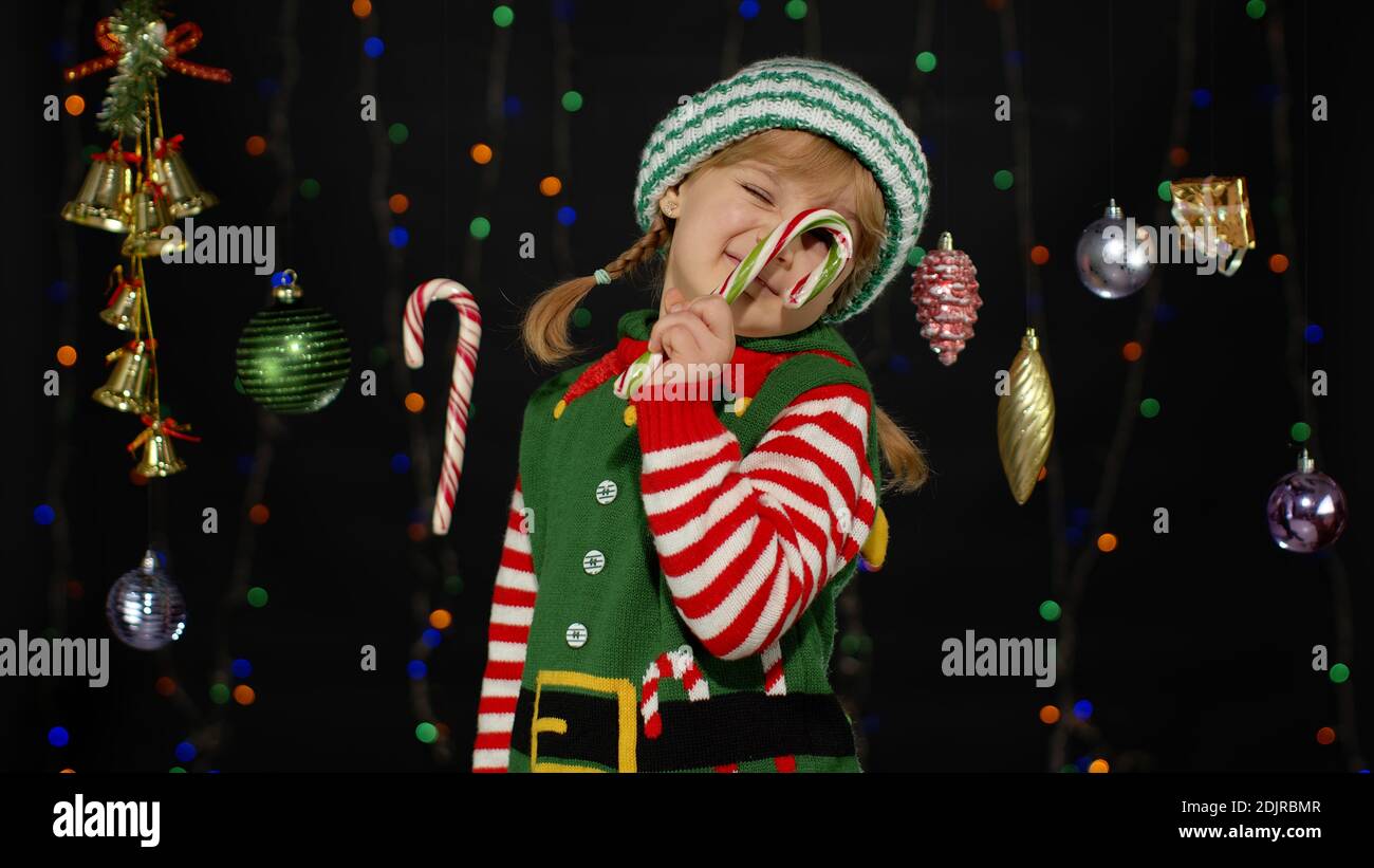 Shy kid girl in Christmas elf Santa Claus helper costume with candy ...