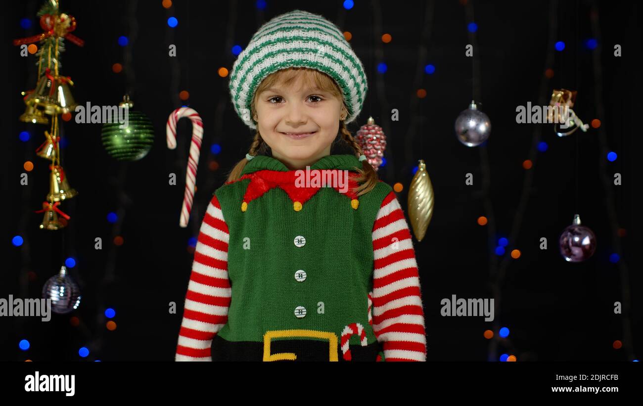 Shy shamed child girl in Christmas elf Santa helper costume posing and ...