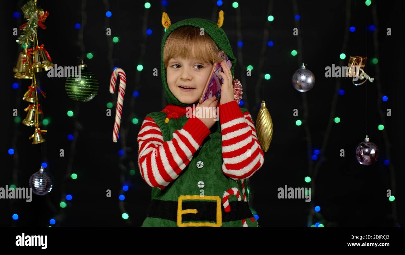 Joyful kid child girl in Christmas elf Santa helper costume making call ...