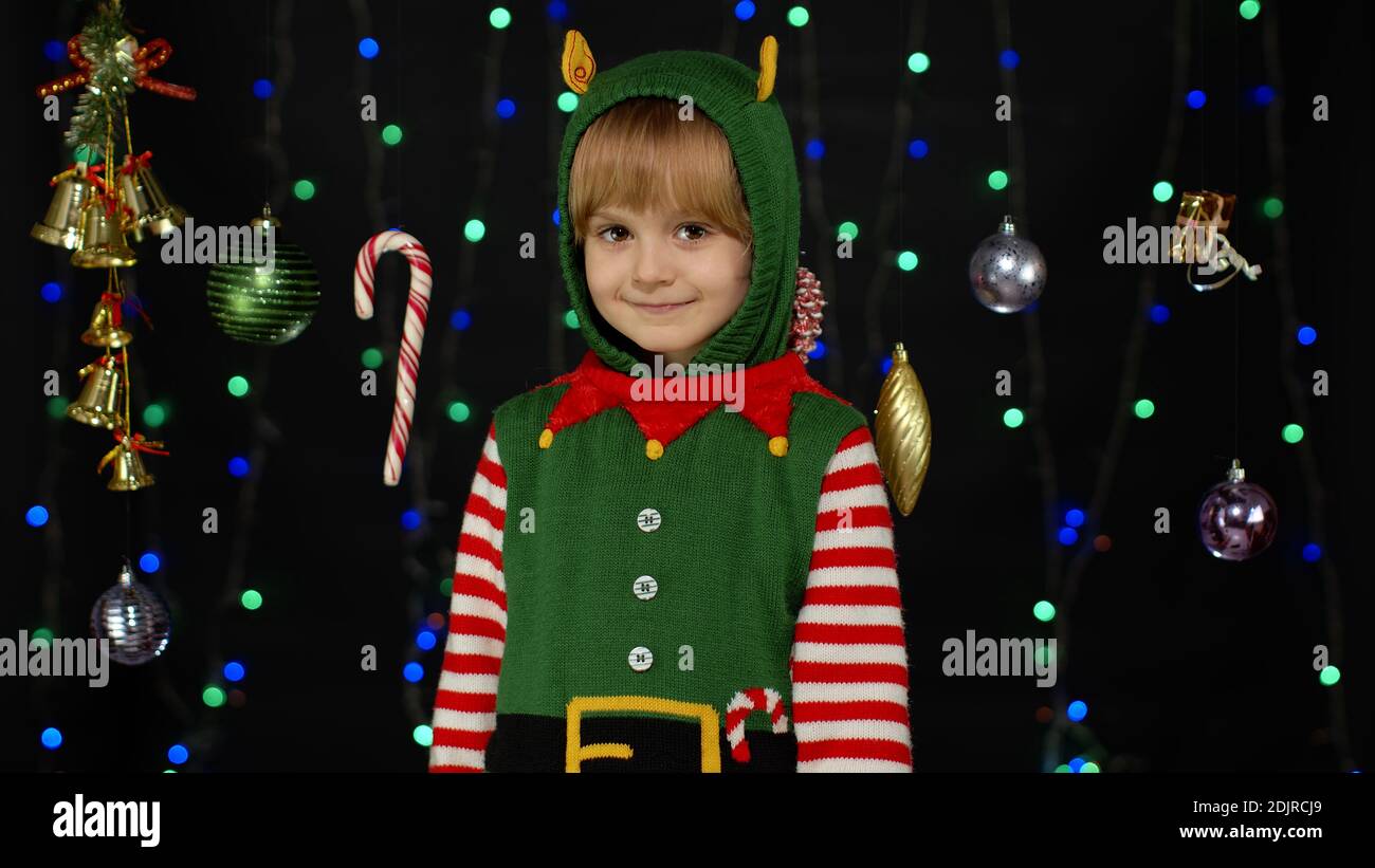 Shy shamed child girl in Christmas elf Santa helper costume posing and ...