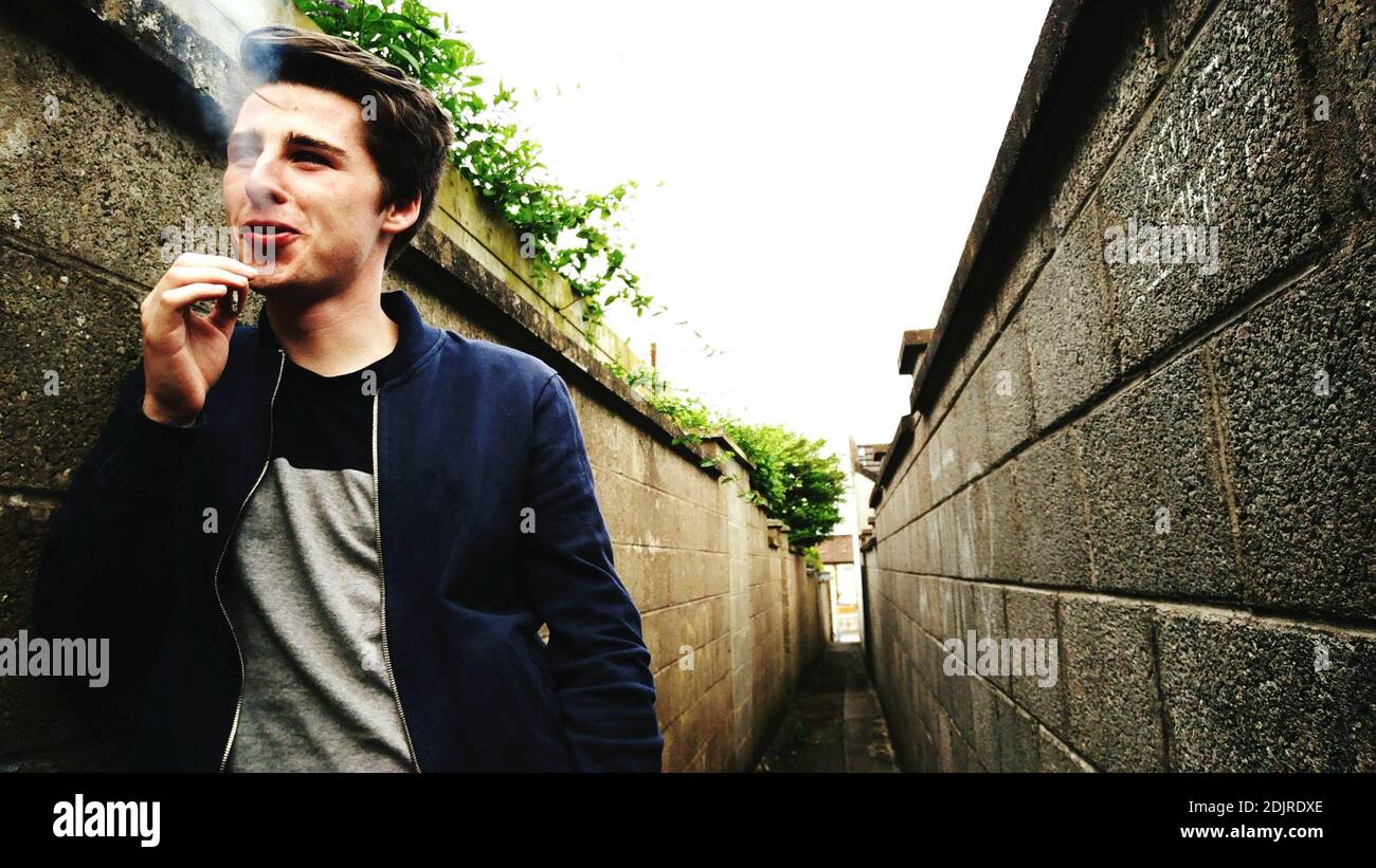 Man in alley smoking cigarette hi-res stock photography and images - Alamy