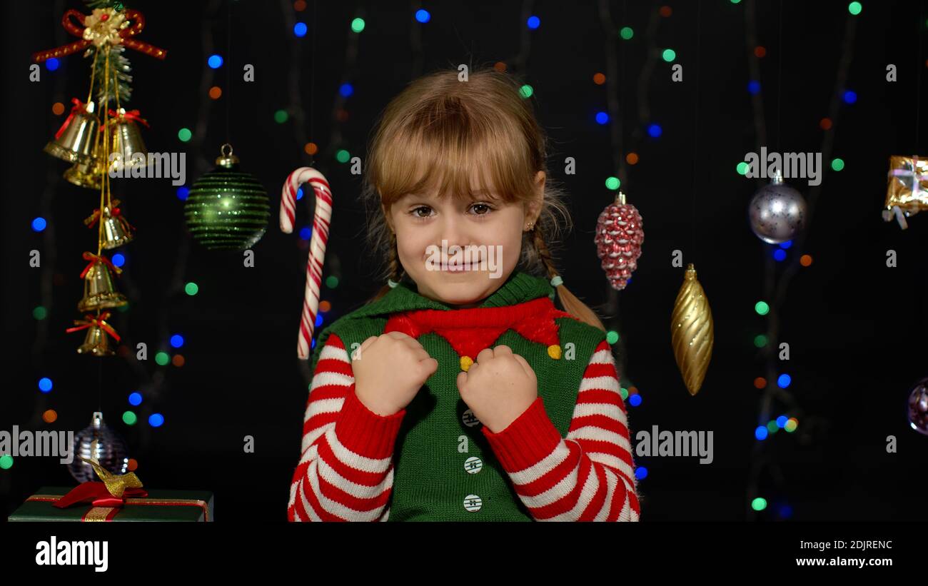 Shy shamed child girl in Christmas elf Santa helper costume posing and ...