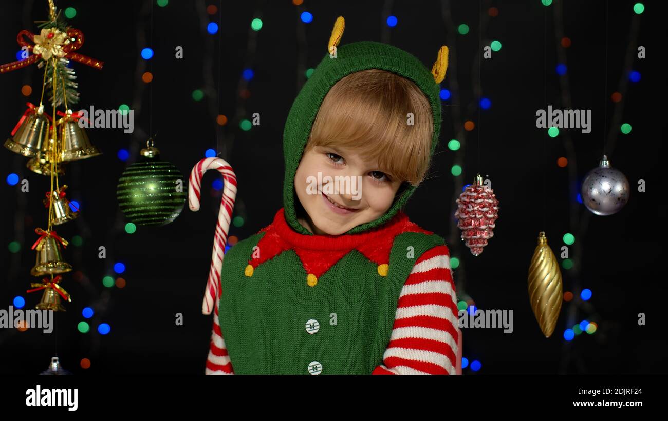 Shy shamed child girl in Christmas elf Santa helper costume posing and ...