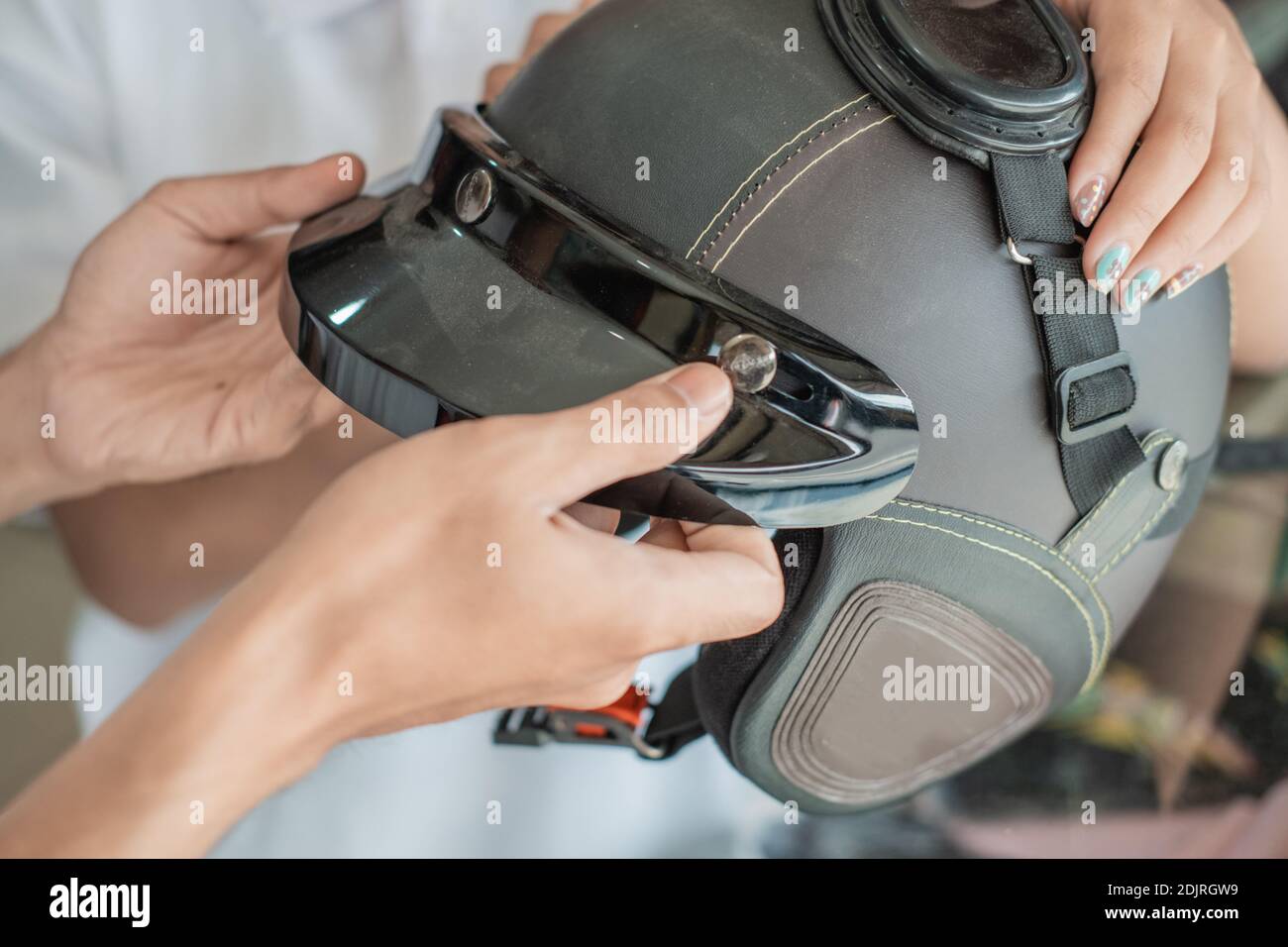female and male hands holding helmet against helmet display rack ...