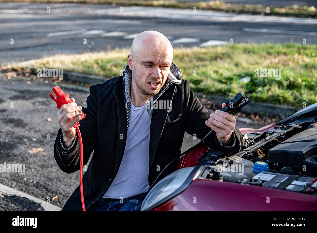 The devastated driver is trying to start his broken red car with the ...