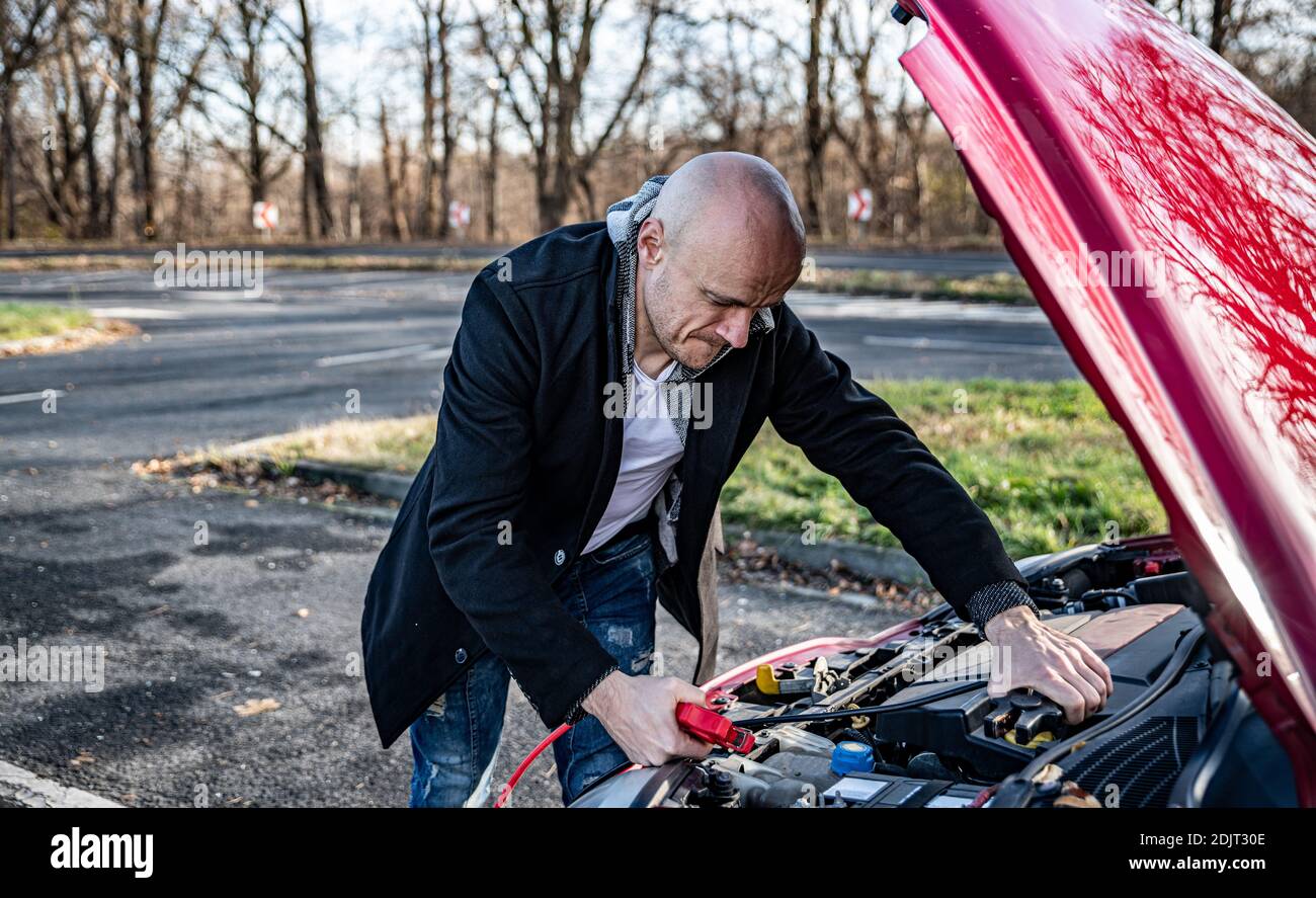 The driver is using jumper cables to try to start the broken car Stock ...