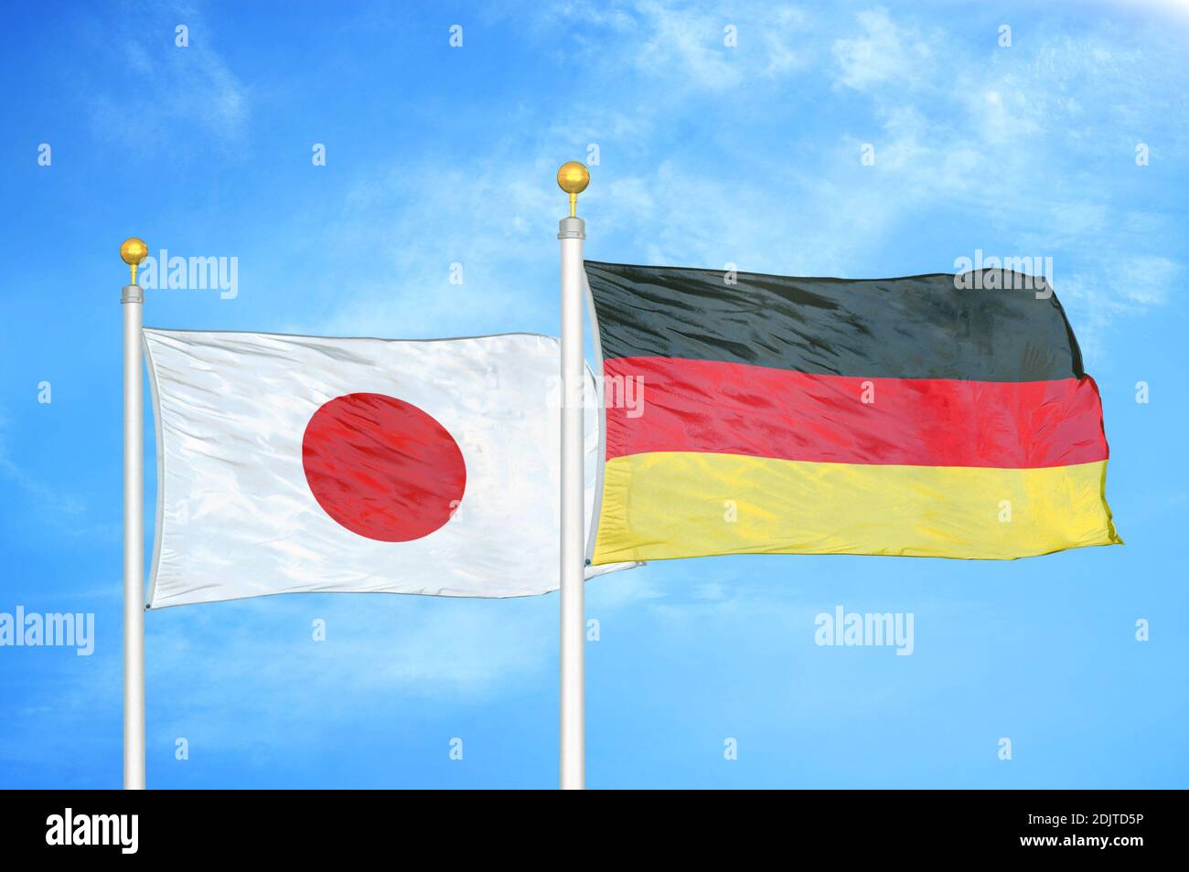 Japan and Germany two flags on flagpoles and blue cloudy sky Stock ...
