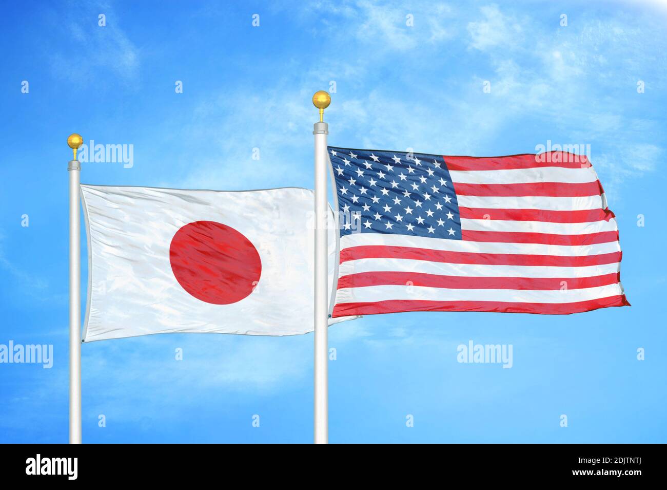 Japan and United States two flags on flagpoles and blue cloudy sky ...