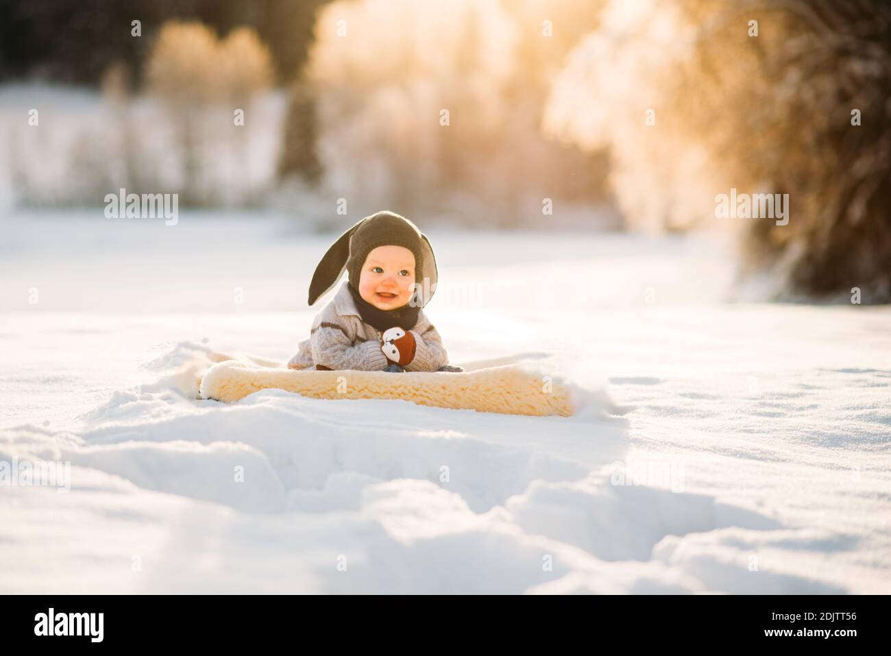 Cute baby smiling sitting on snow during sunset in Norwegian forest ...