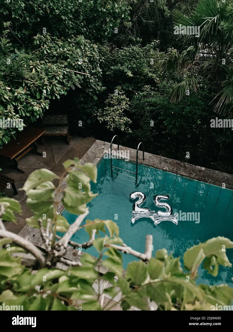 Floating balloons, silver 25 number in the cyan swimming pool. Green ...