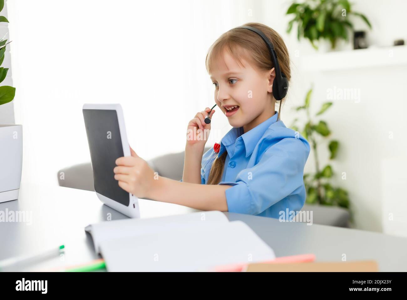 Smart little schoolgirl with digital tablet in a classroom. Child in an ...