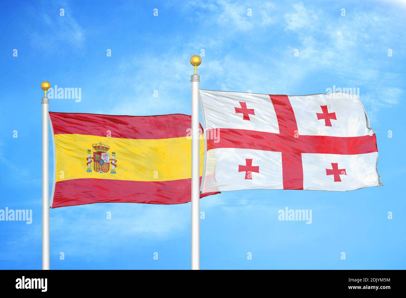 Spain and Georgia two flags on flagpoles and blue cloudy sky Stock ...