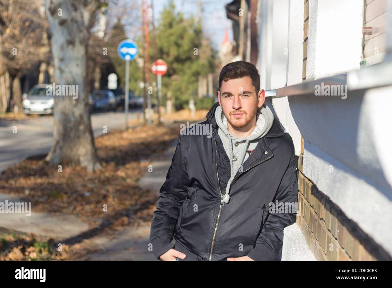 Young man leaning against wall Stock Photo - Alamy
