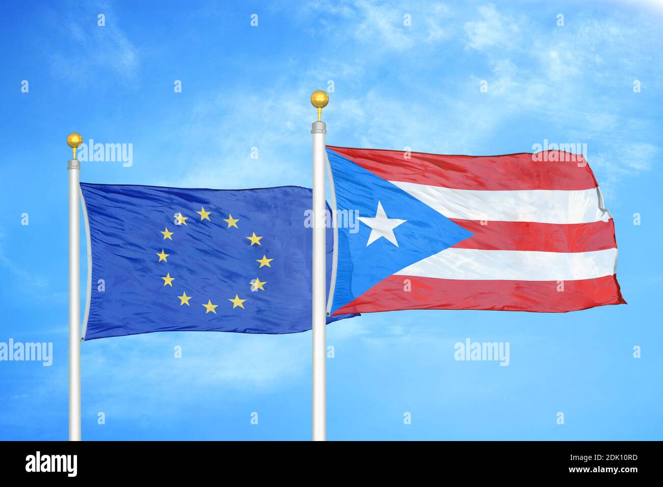 European Union and Puerto Rico two flags on flagpoles and blue cloudy ...