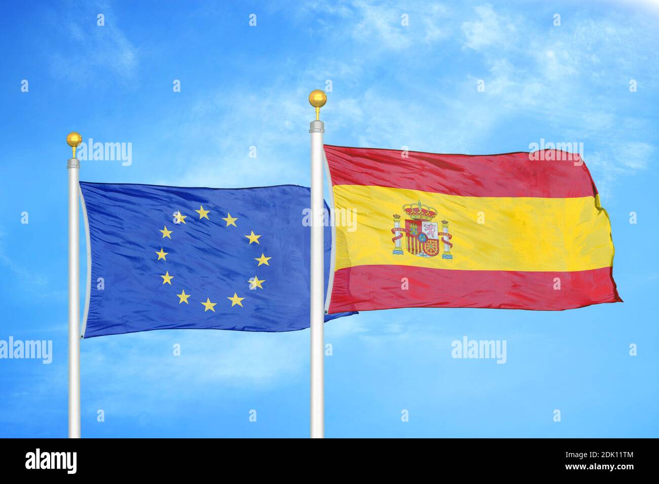 European Union and Spain two flags on flagpoles and blue cloudy sky ...