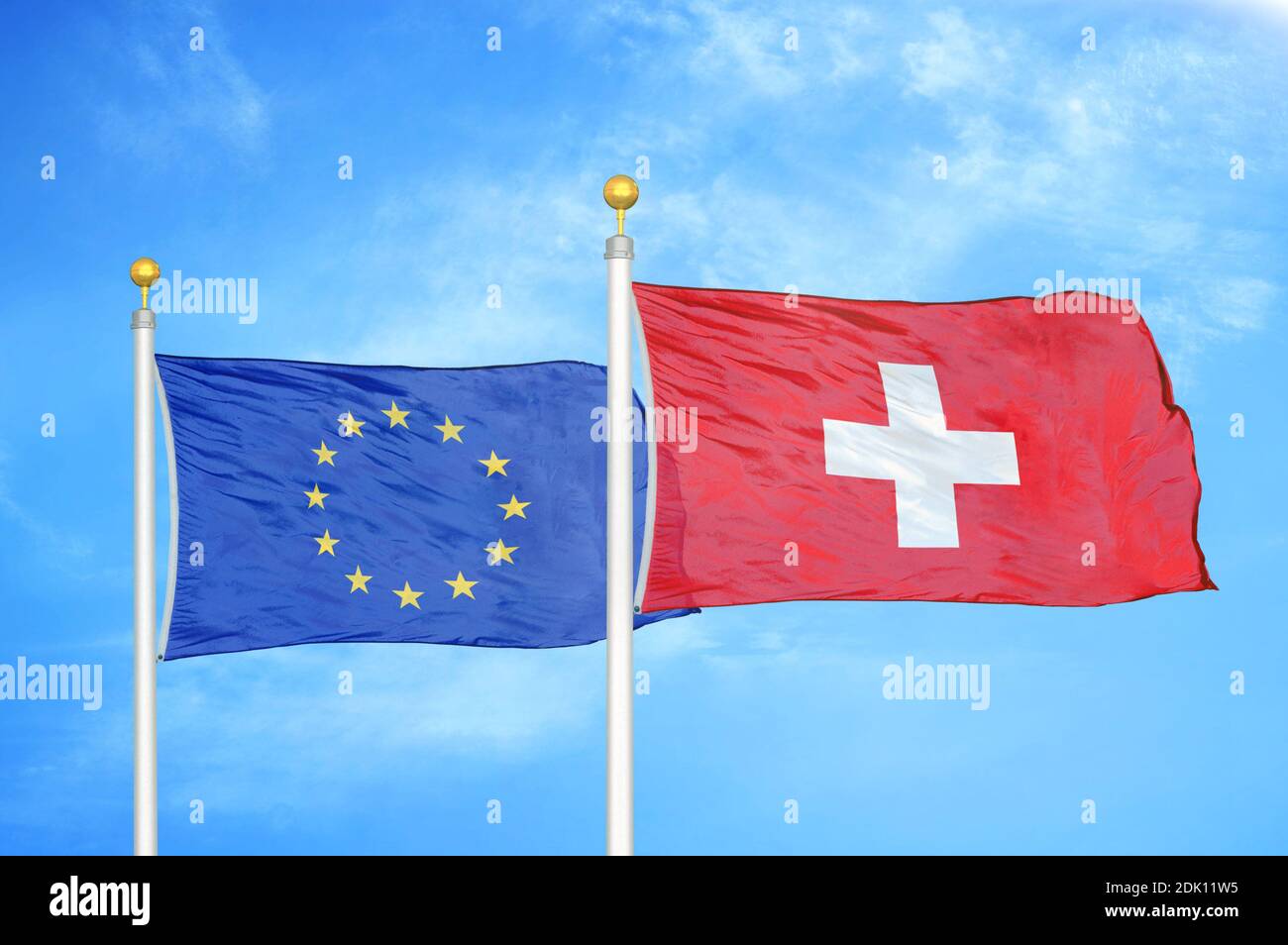 European Union and Switzerland two flags on flagpoles and blue cloudy ...