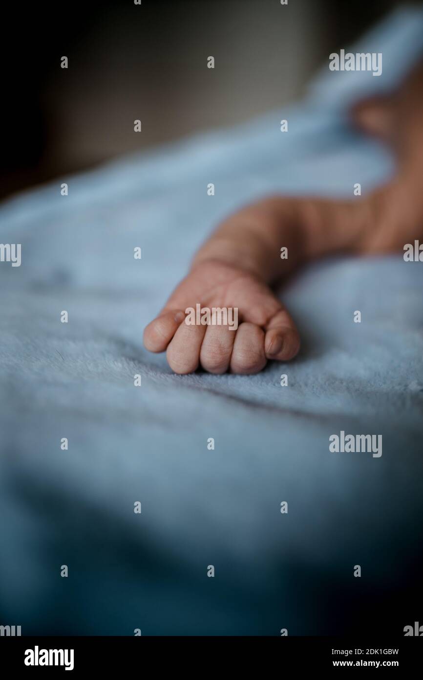 A vertical closeup shot of a baby hand laying on the bed. Cute baby ...